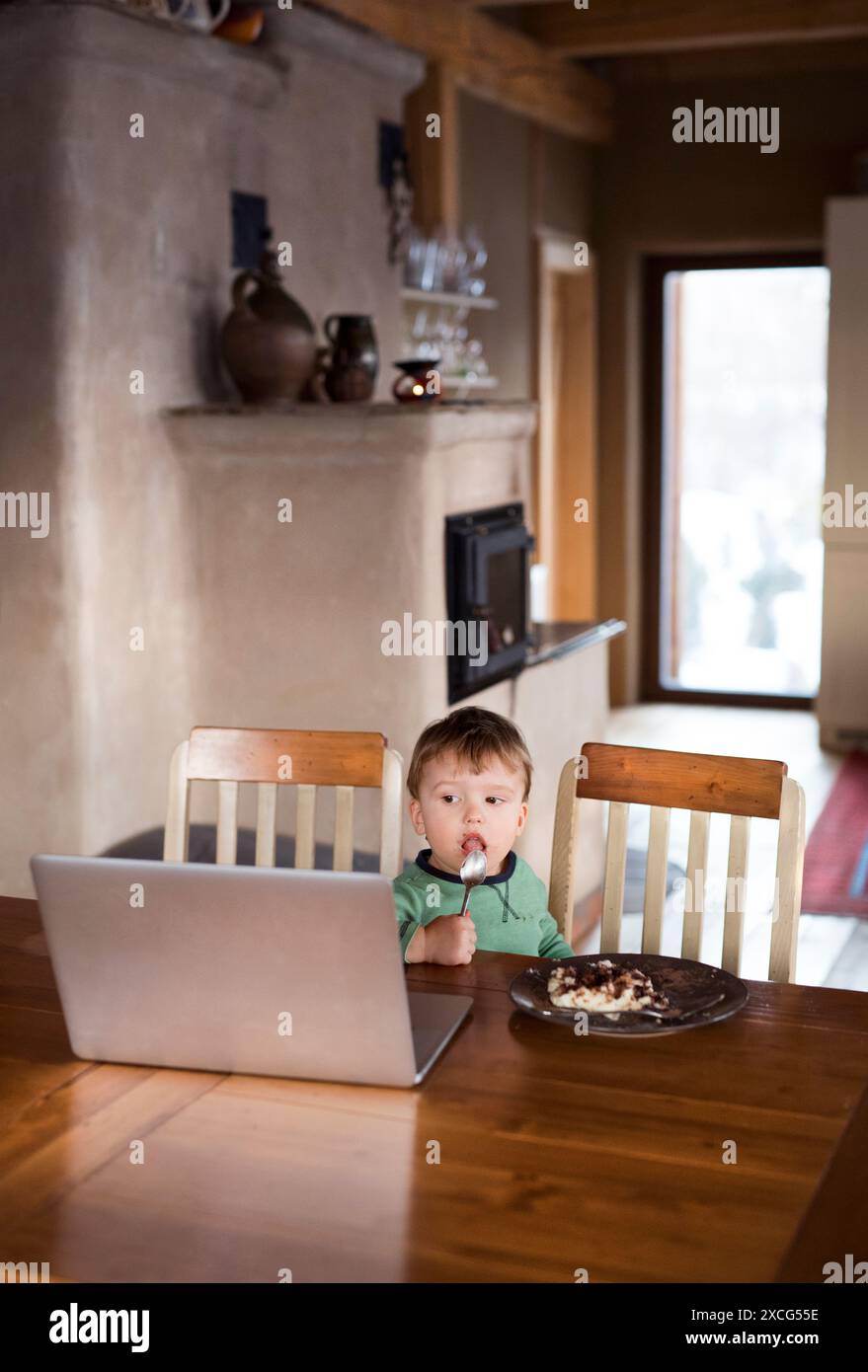 Boy watching cartoon on laptop while eating porridge Stock Photo - Alamy