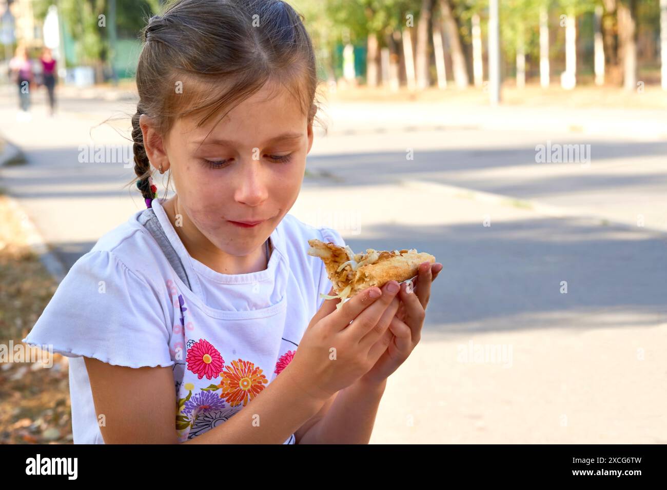 Snack. Cute grimy child girl eating a piece of pizza Stock Photo - Alamy
