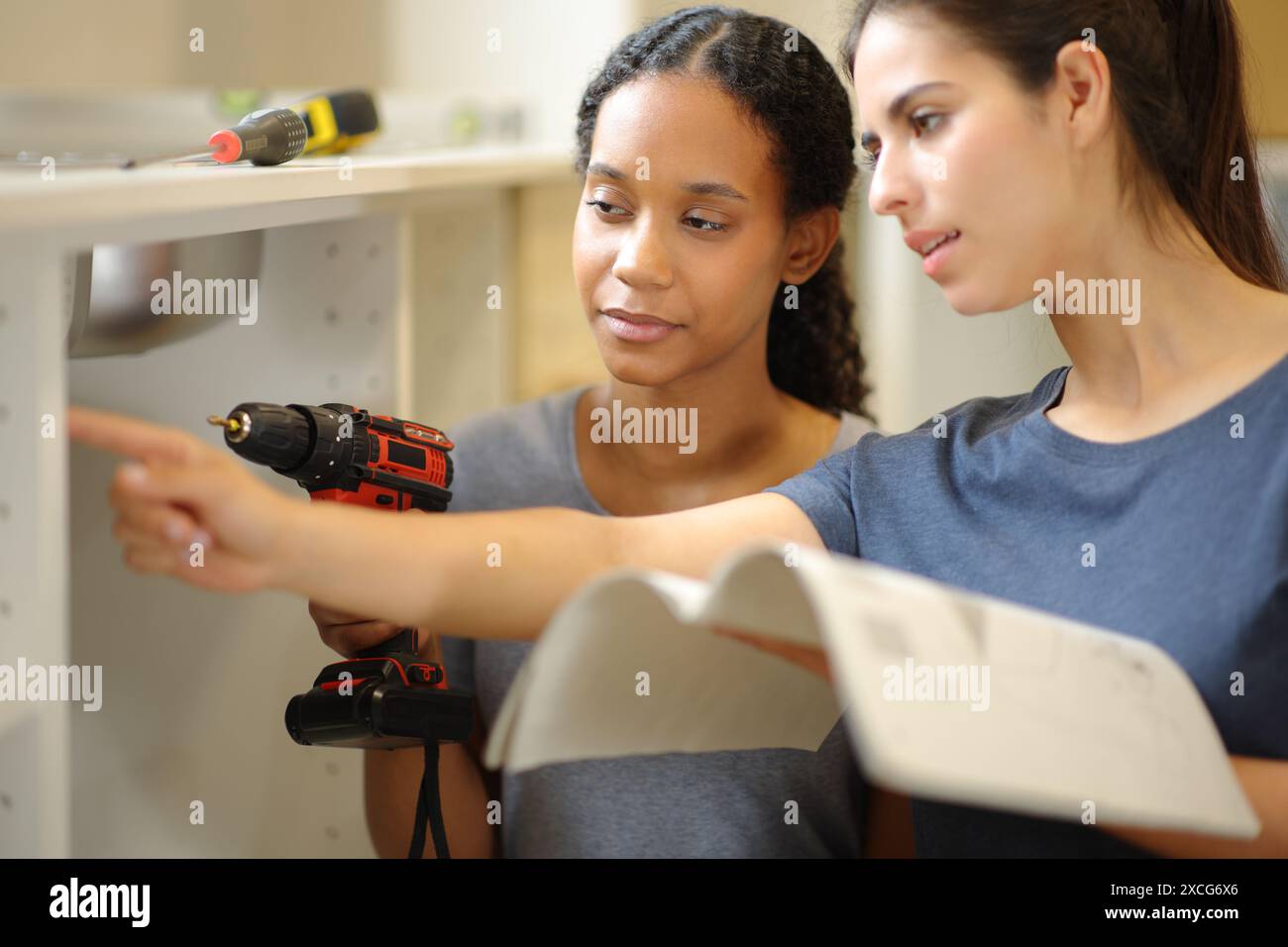 Roommates installing furniture checking instructions manual in the ...
