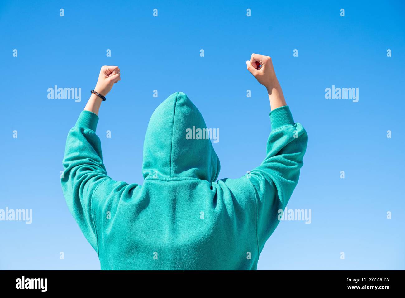 a young person seen from the back, dressed in a green hooded sweater ...