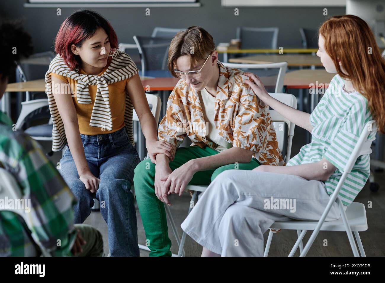 Ethnically diverse teen girls supporting sad boy during group therapy ...