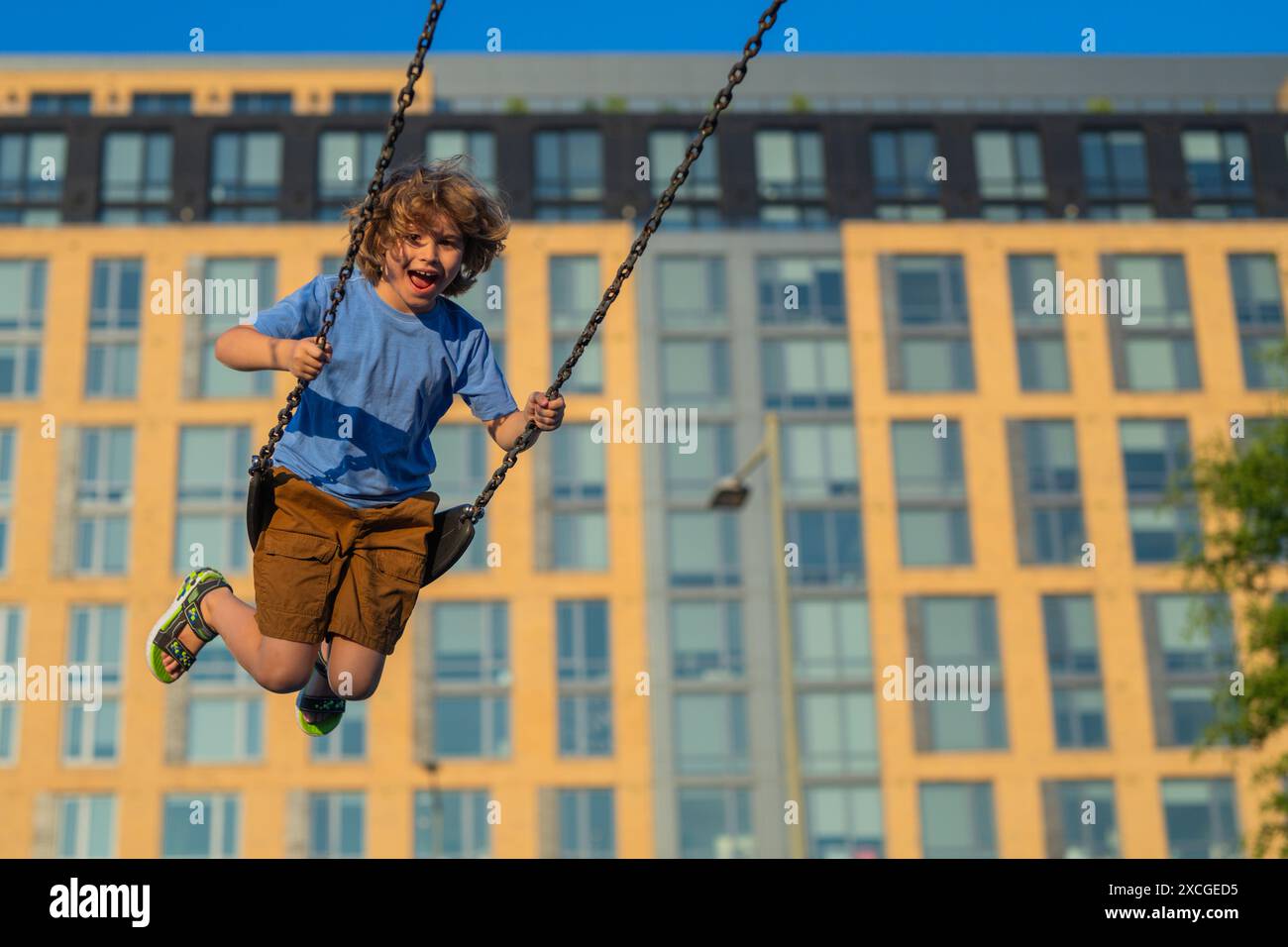 Kid swinging on chain swing on city kids playground. Swing ride. Cute ...