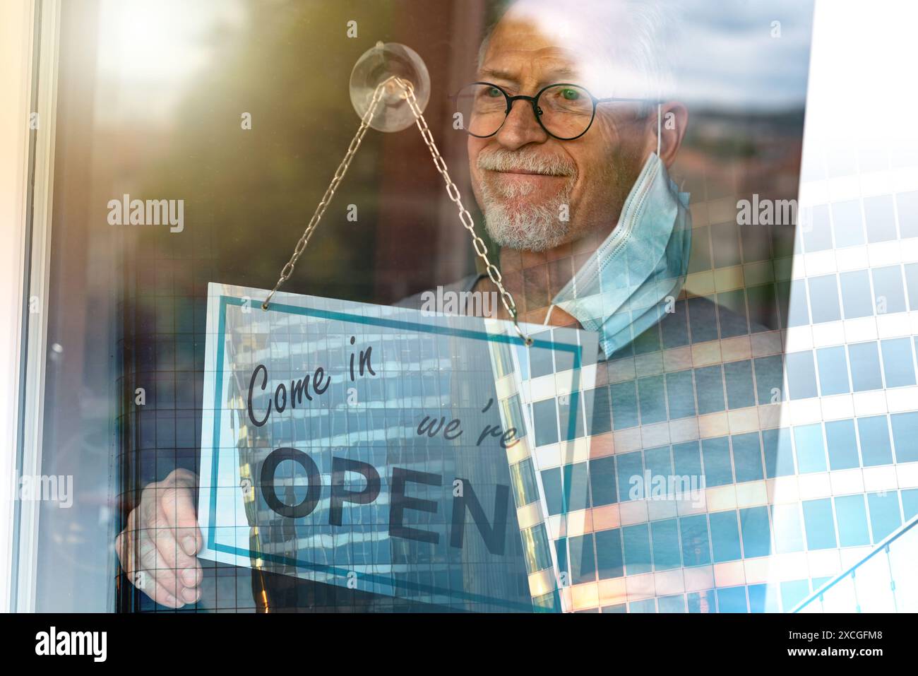 Store owner hanging come in we're open sign on window; multiple ...