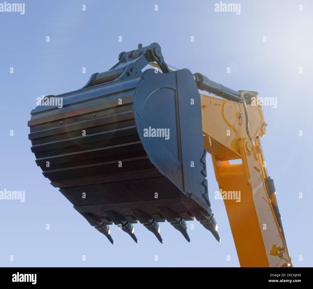 Scoop and hydraulic arm of an excavator, isolated on clear blue sky ...