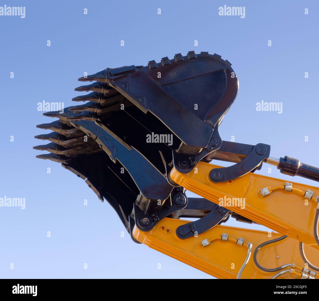 Scoop and hydraulic arm of an excavator, isolated on clear blue sky ...