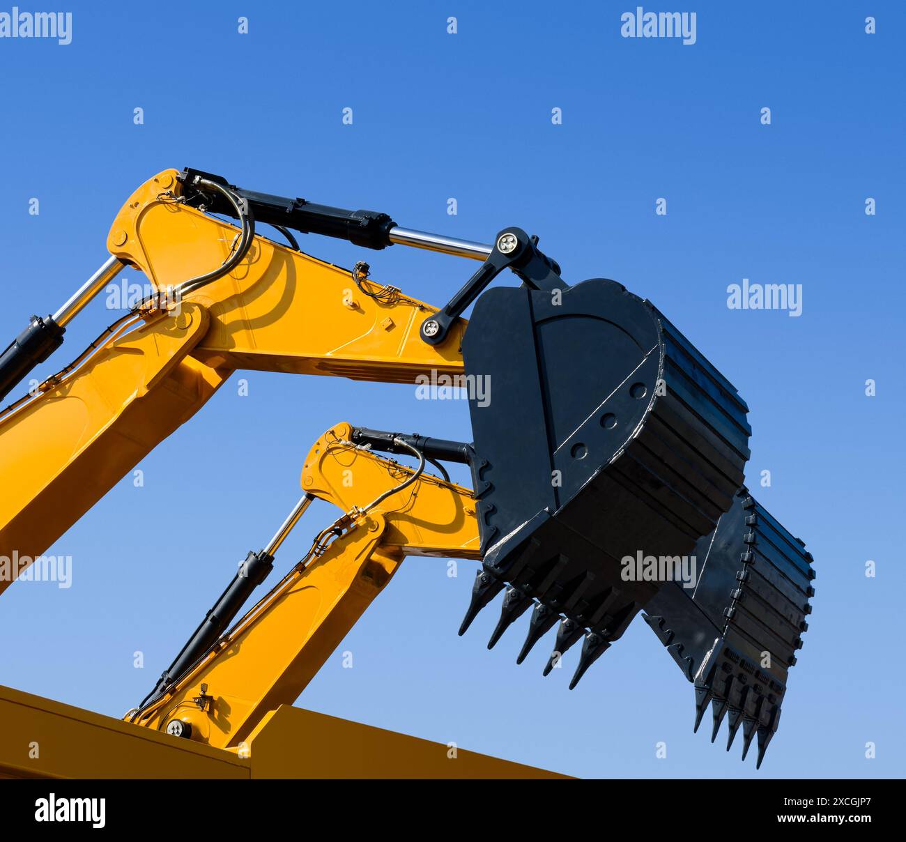 Scoop and hydraulic arm of an excavator, isolated on clear blue sky ...