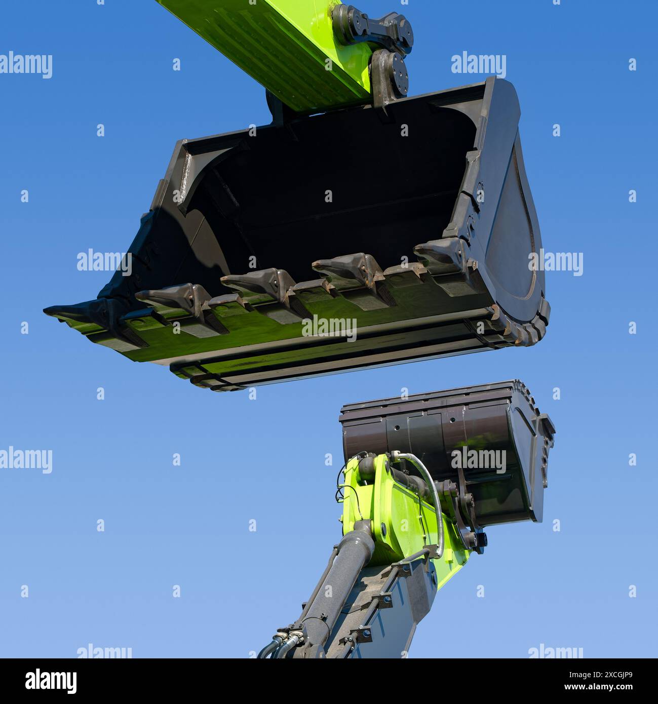 Scoop and hydraulic arm of an excavator, isolated on clear blue sky ...