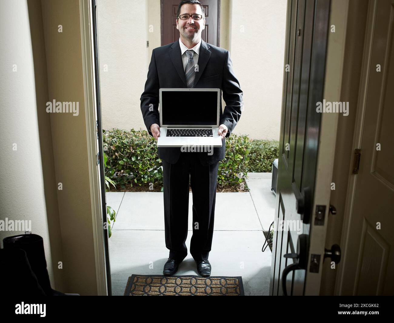 Business man at the door holding a laptop computer Stock Photo - Alamy