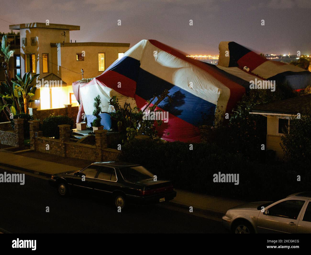 A home at night in San Diego is tented as it is fumigated inside to ...