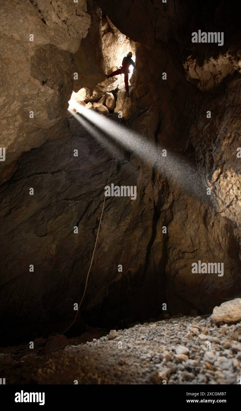 Cave Explorer about to descend into daylight lit entrance chamber to a ...