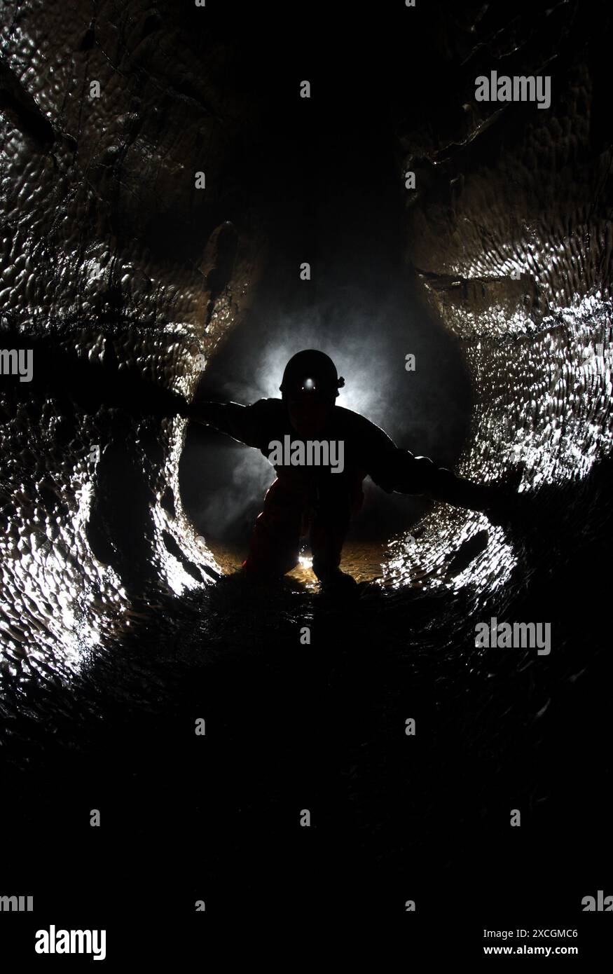 Cave explorer poses for a photograph in a well formed passage ...