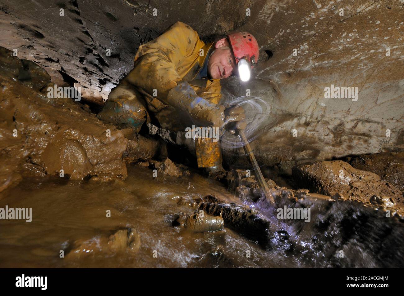 A British cave explorer tries to work a trench out of the mud filled ...
