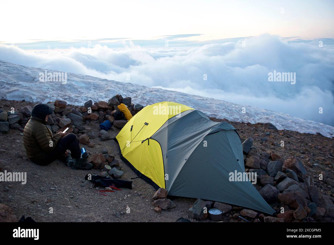 Mountain climber sitting near tent at Camp Curtis on Mount Rainier ...