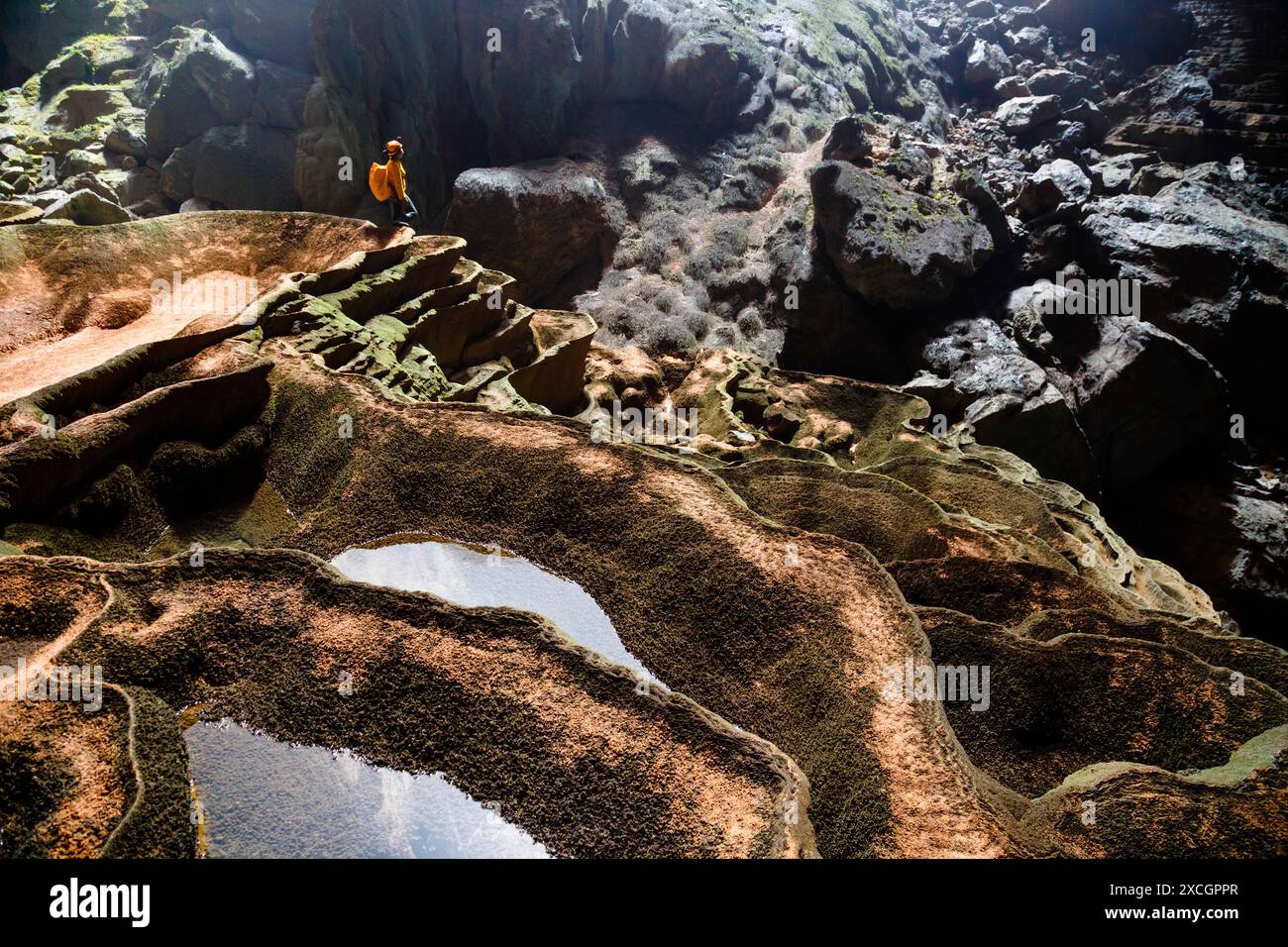 A cave explorer stands on rimstone formations in Hang Son Doong ...