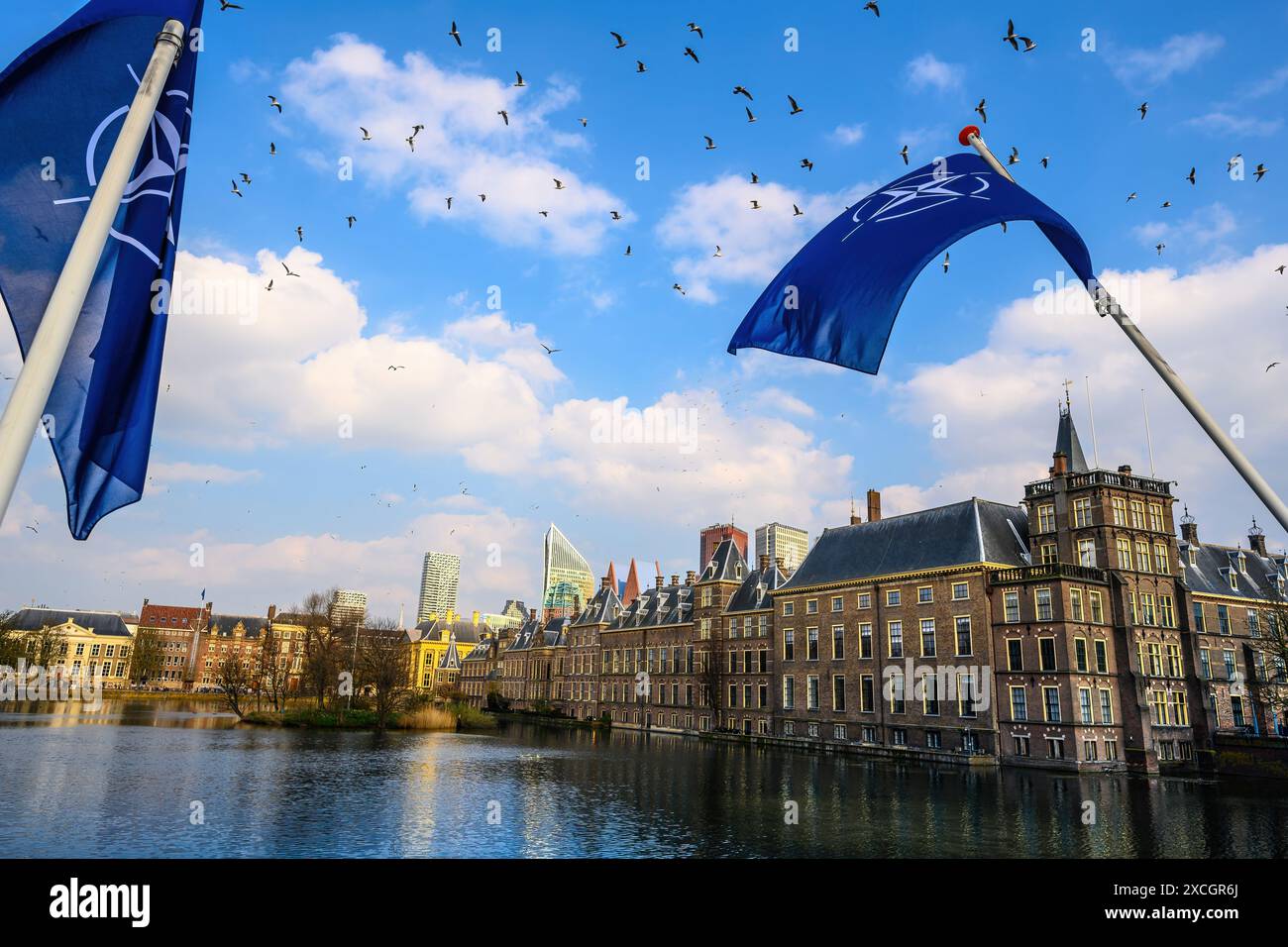 Waving NATO flag in the center of Hague sky with dutch river channels ...