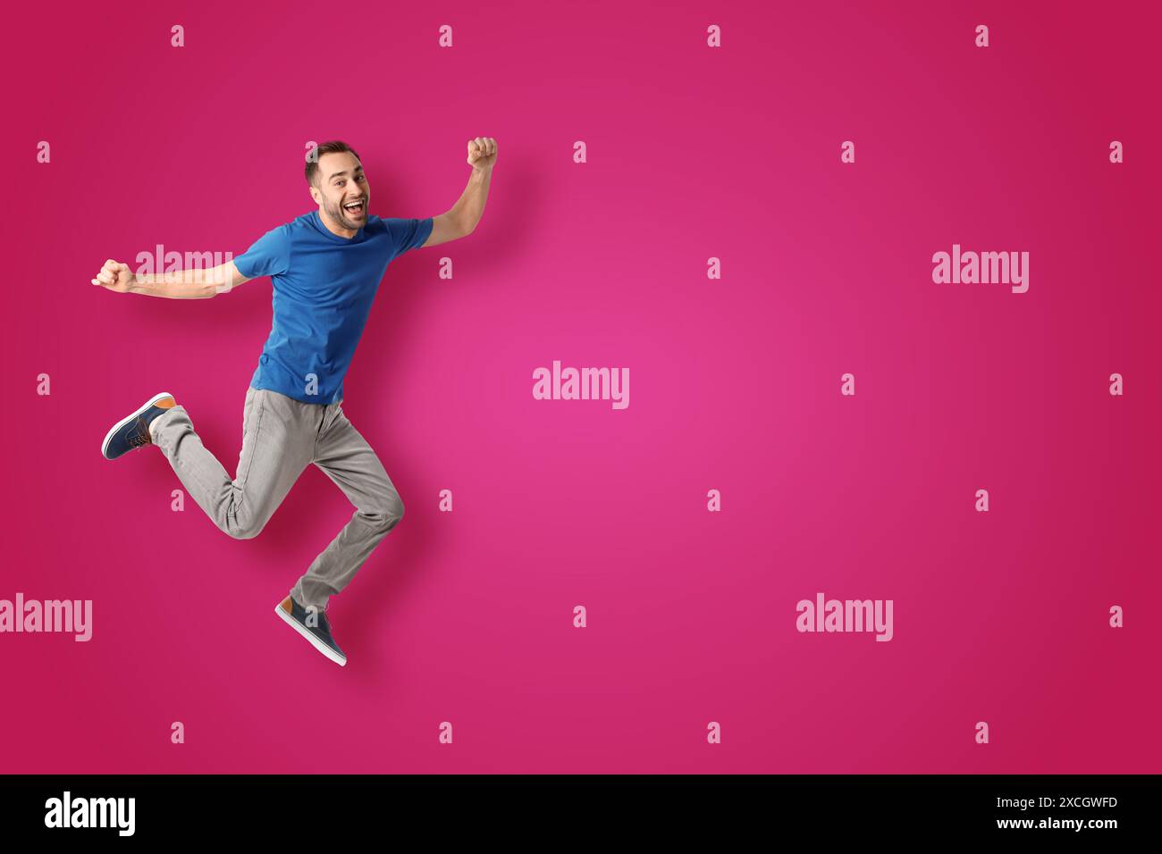 Positive young man jumping on hot pink background. Space for text Stock ...