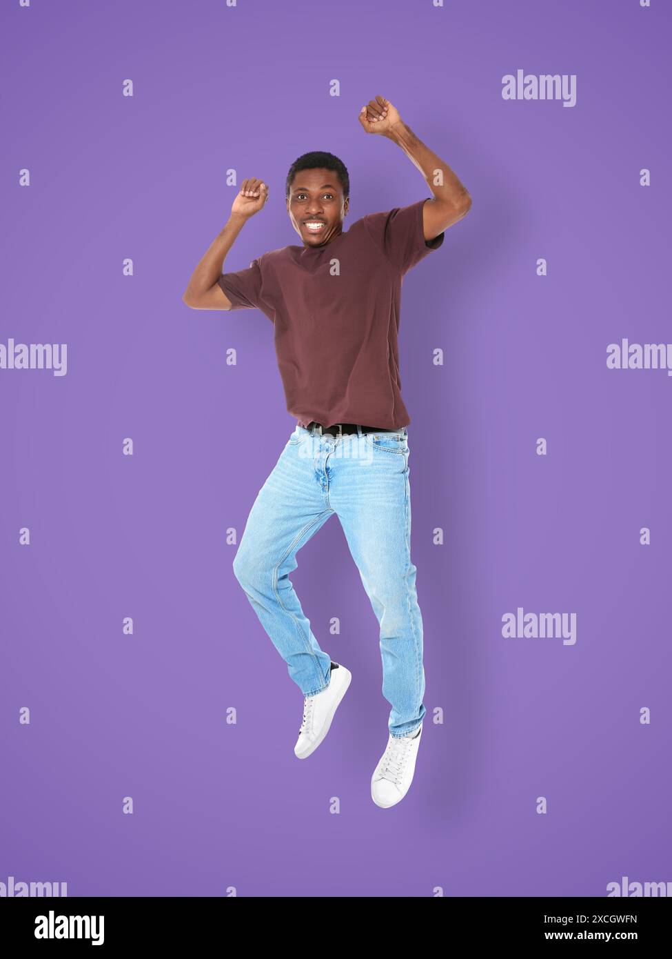 Positive young man jumping on purple background Stock Photo - Alamy