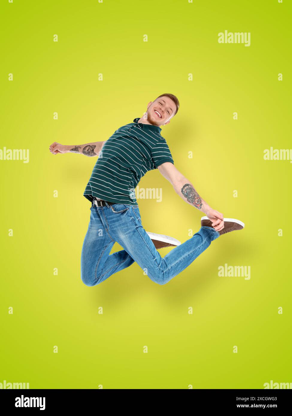 Positive young man jumping on light green background Stock Photo - Alamy