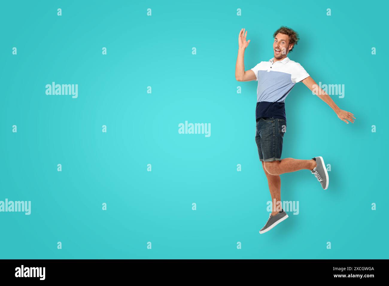 Positive young man jumping on turquoise background. Space for text ...