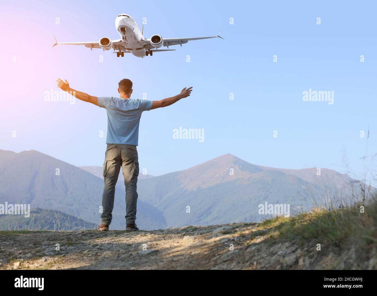 Man looking at airplane flying in sky over mountains during sunrise ...