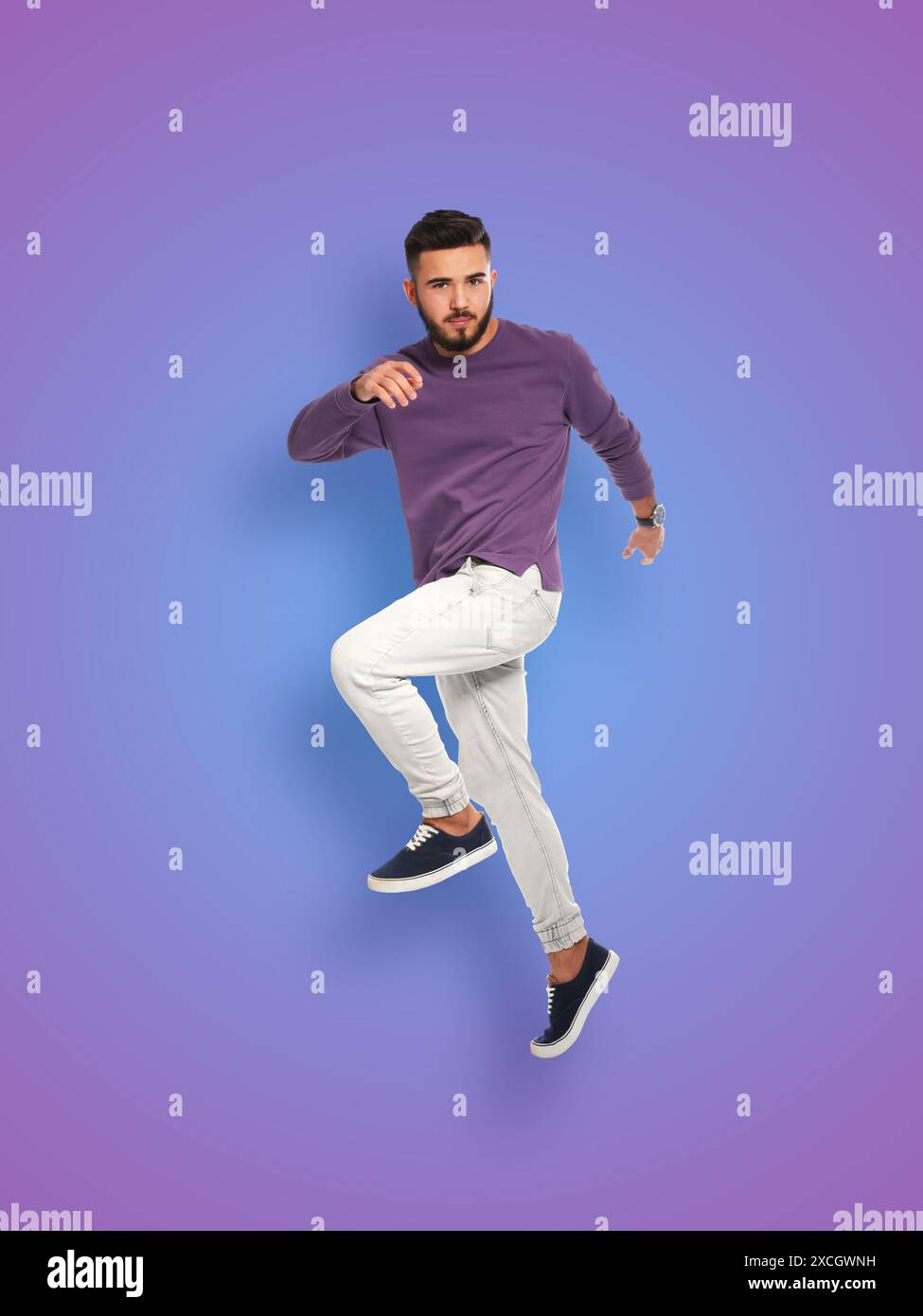 Positive young man jumping on purple gradient background Stock Photo ...