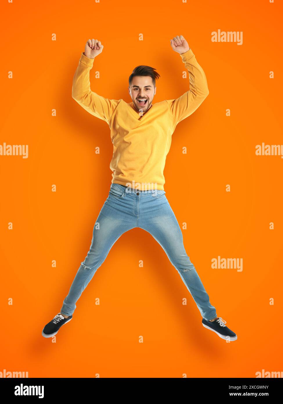 Positive young man jumping on orange background Stock Photo - Alamy