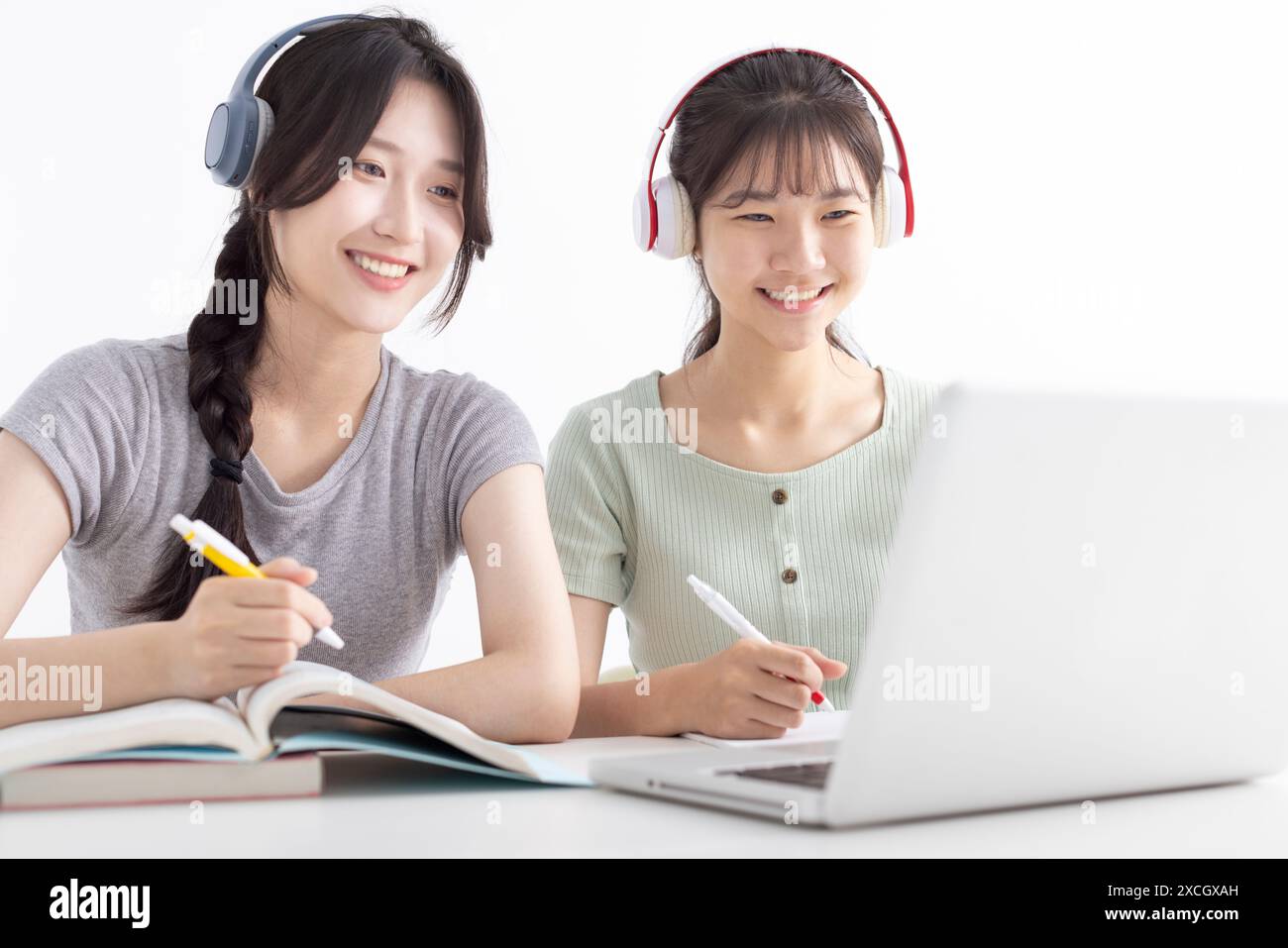Happy young girls with wireless headphones looking at laptop screen ...