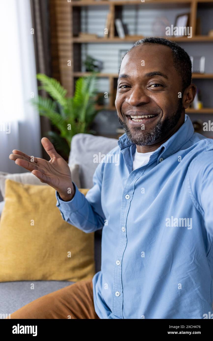 Smiling man making a video call from the comfort of his home living ...