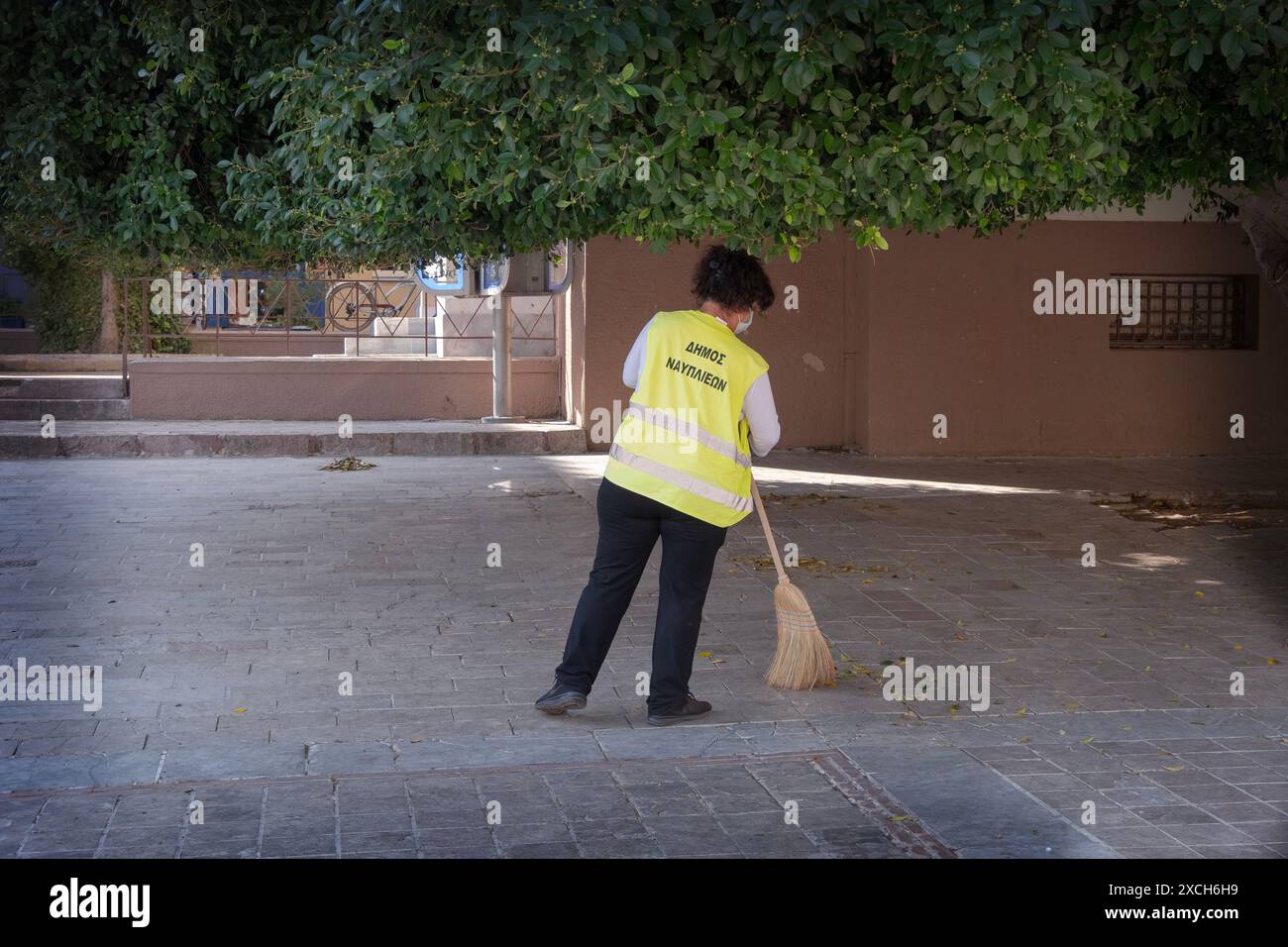 A middle aged Greek worker wearing a surgical mask & reflective vest ...