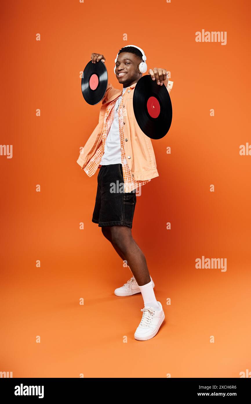 Handsome African American man holding vinyl record on orange backdrop ...
