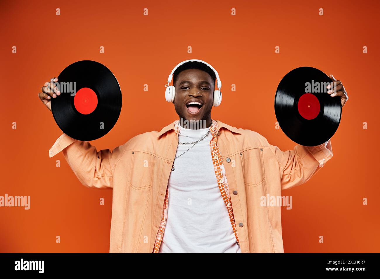 Stylish African American man holding vinyl records against orange ...