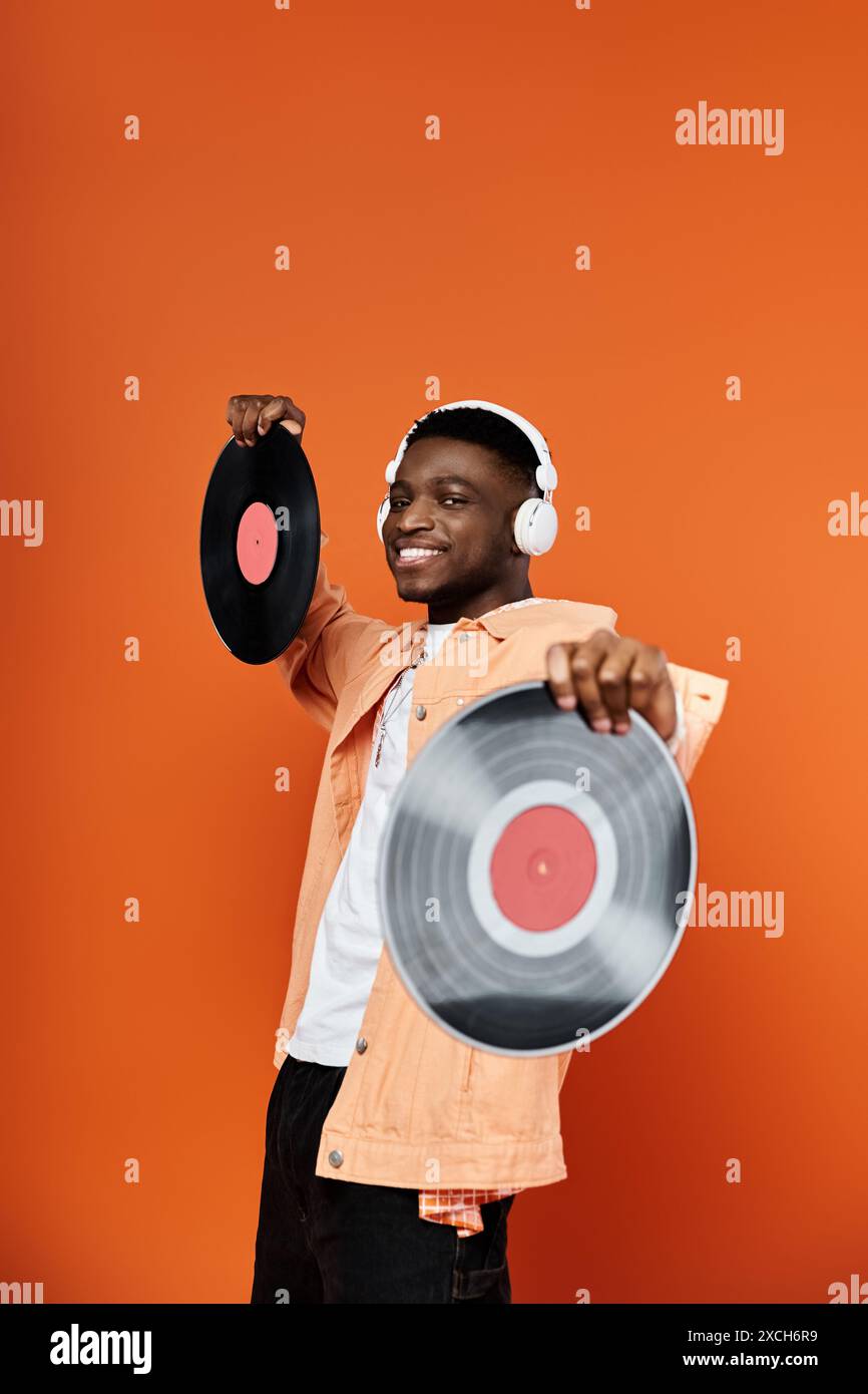 Stylish young African American man holding vinyl record on orange ...