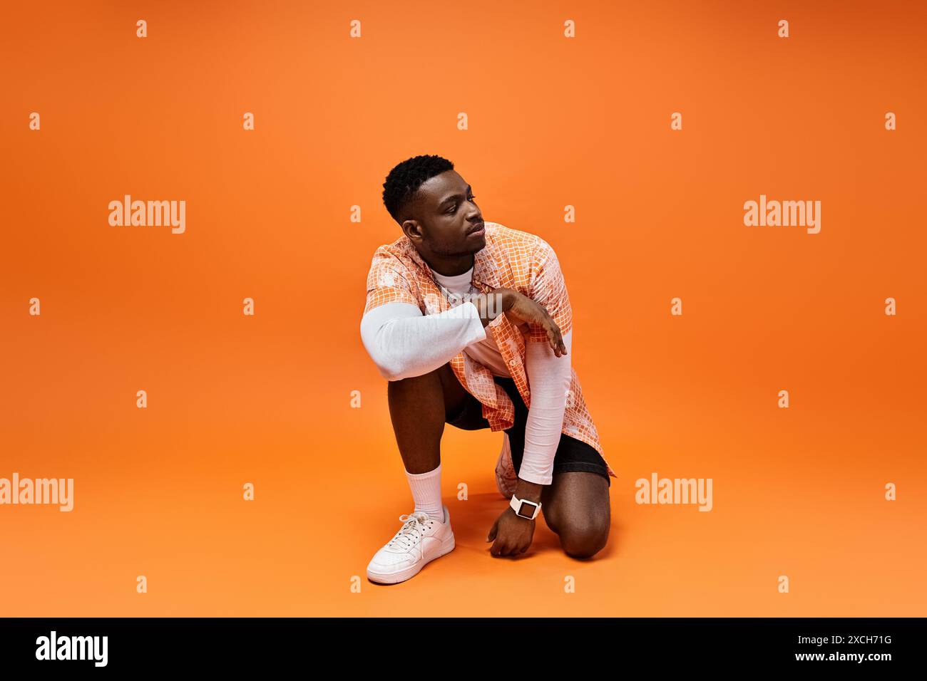 Handsome African American man in fashionable attire crouching on vivid ...