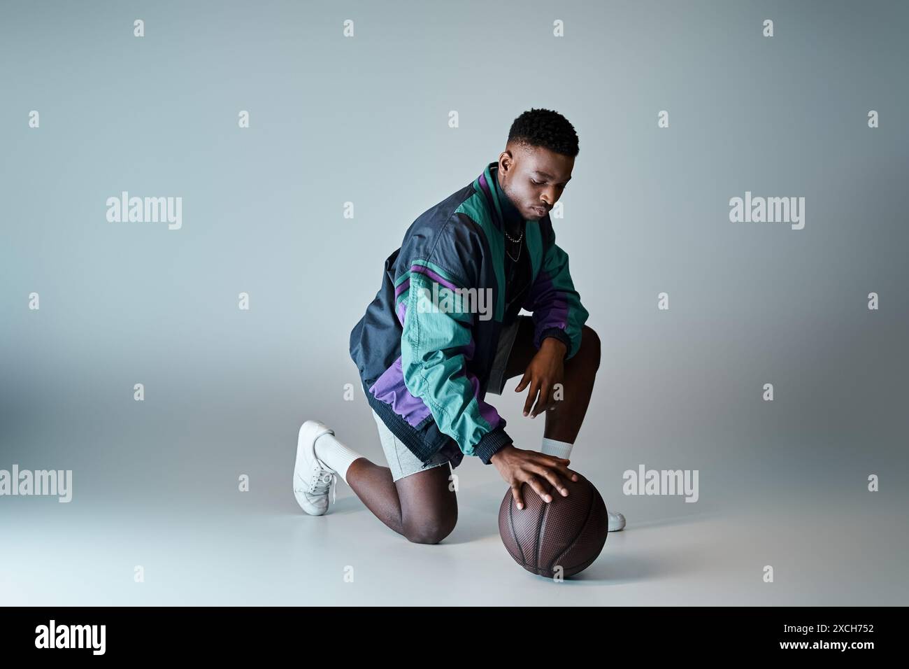 Fashionable young African American man in stylish attire crouching with ...