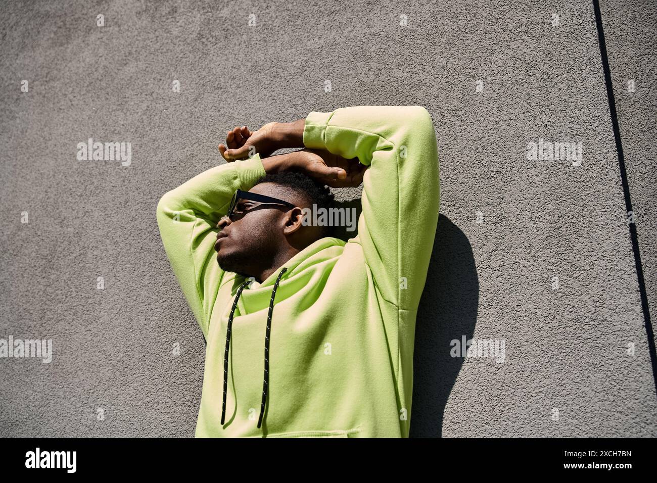 Stylish African American man leaning against a wall in a lime green ...
