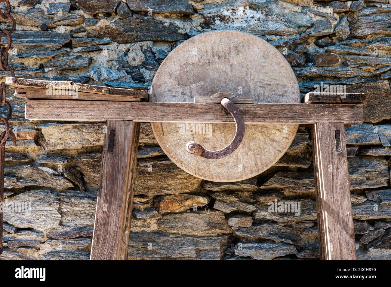 Old grindstone mounted on wooden frame with stone wall background Stock ...