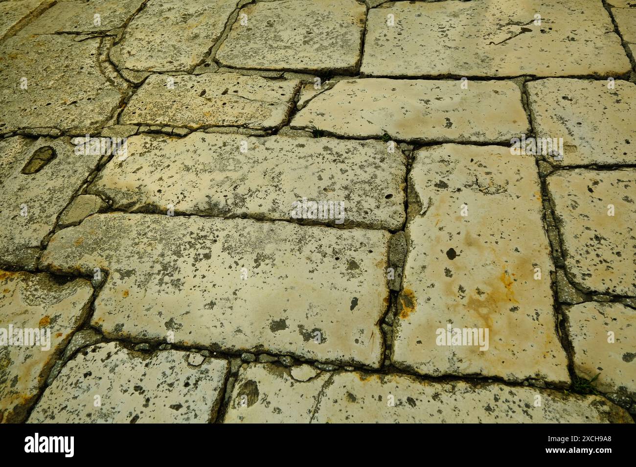 A stone floor with a lot of cracks and holes. The floor is made of ...