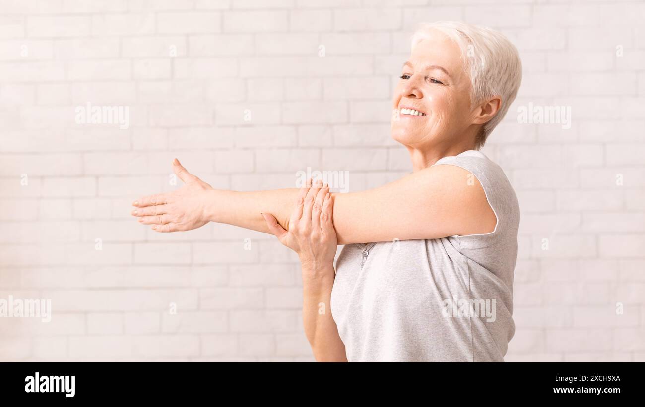 Senior Woman Stretching Arms With Smile in a Bright Room Stock Photo ...