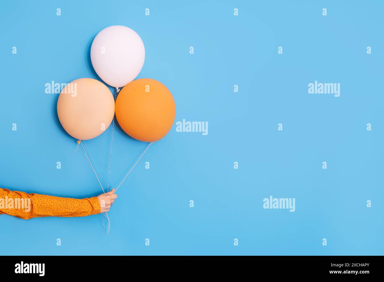 Hand holding helium balloons against blue background Stock Photo - Alamy