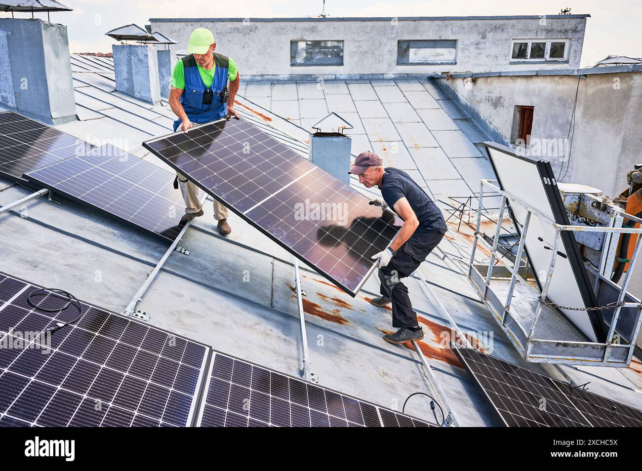 Workers building solar panel system on metal rooftop of house with ...