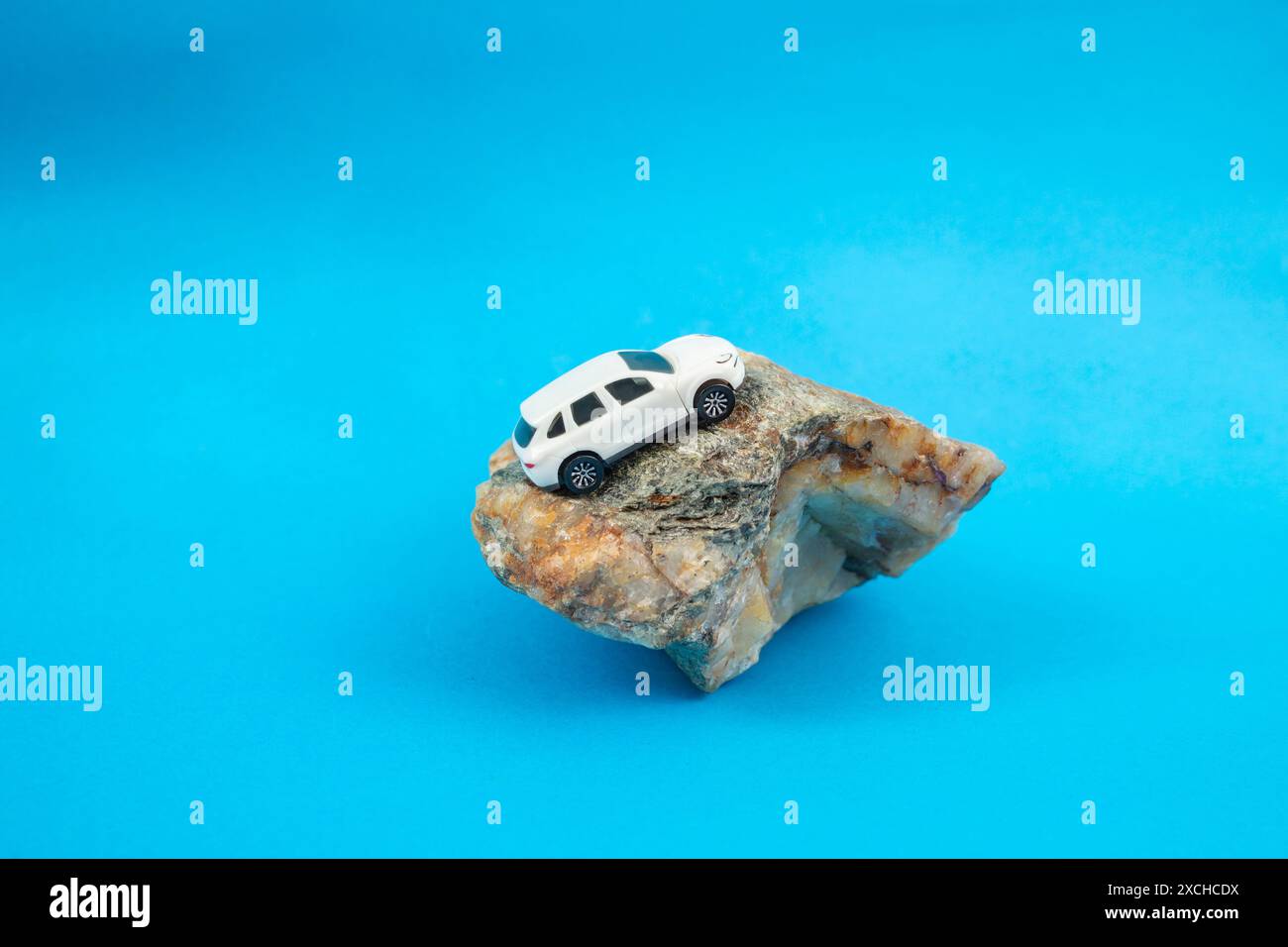 Small generic suv model car climbing a rock in balance on blue Stock ...