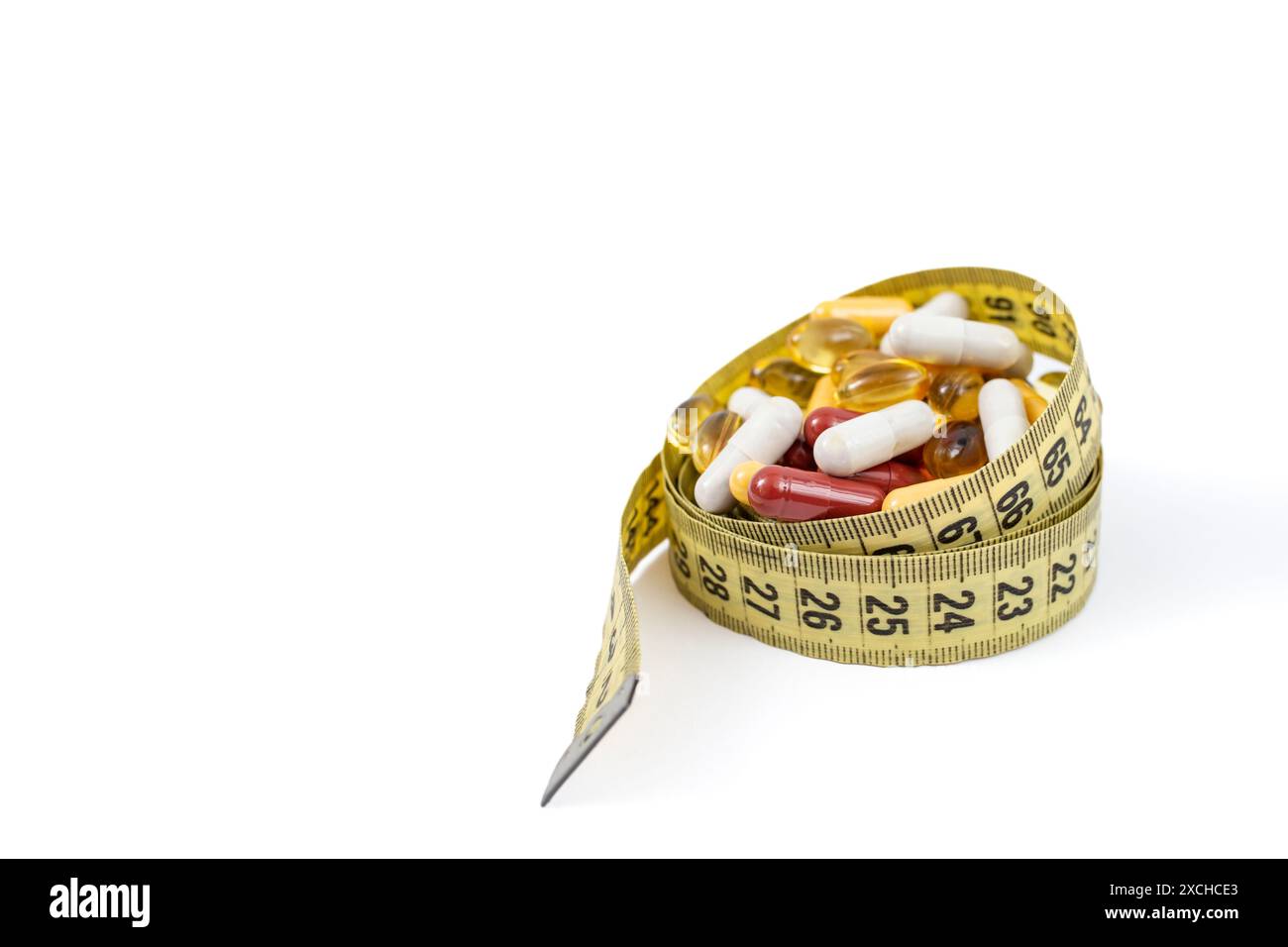 Multiple colored pills and capsules with a coiled measuring tape, close ...