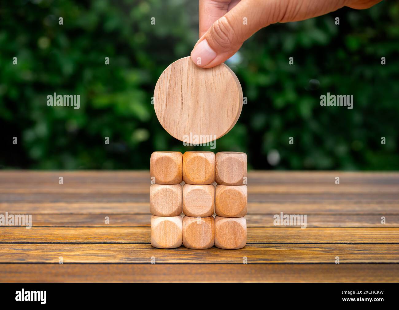 Empty round wood block in hand putting on nine blank wooden cubes ...
