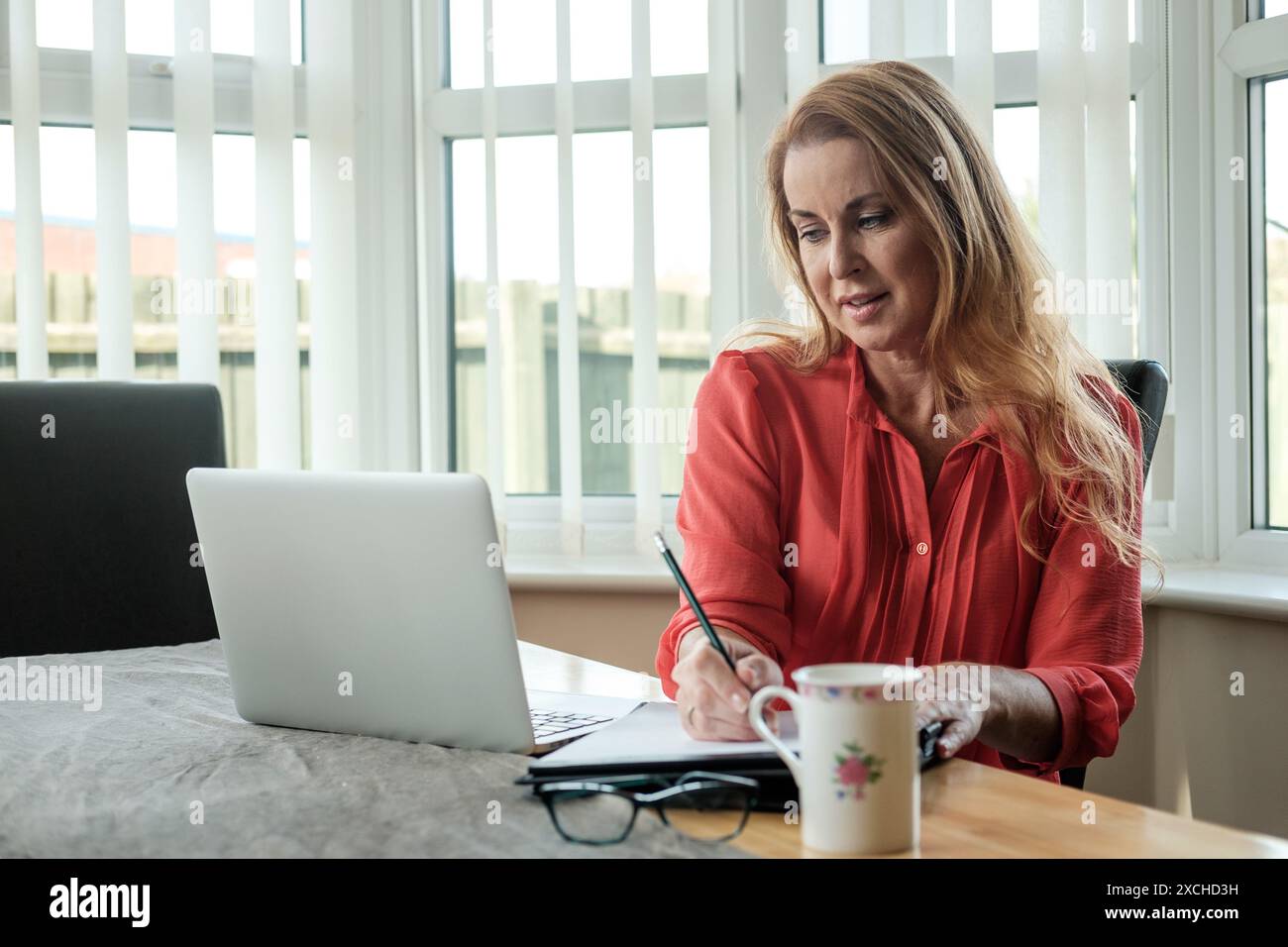 An attractive mid-40s female remote worker getting deep focus work done ...