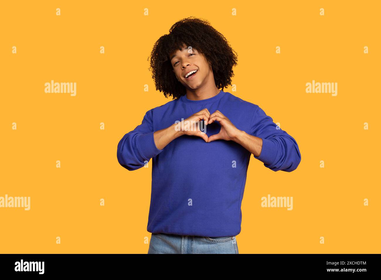 Smiling Man Making Heart Shape With Hands Against Yellow Background ...