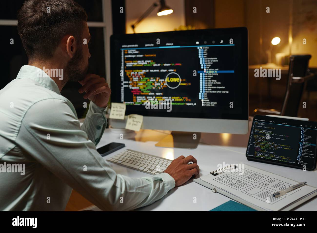 Pensive developer looking at programming code on computer screen Stock ...