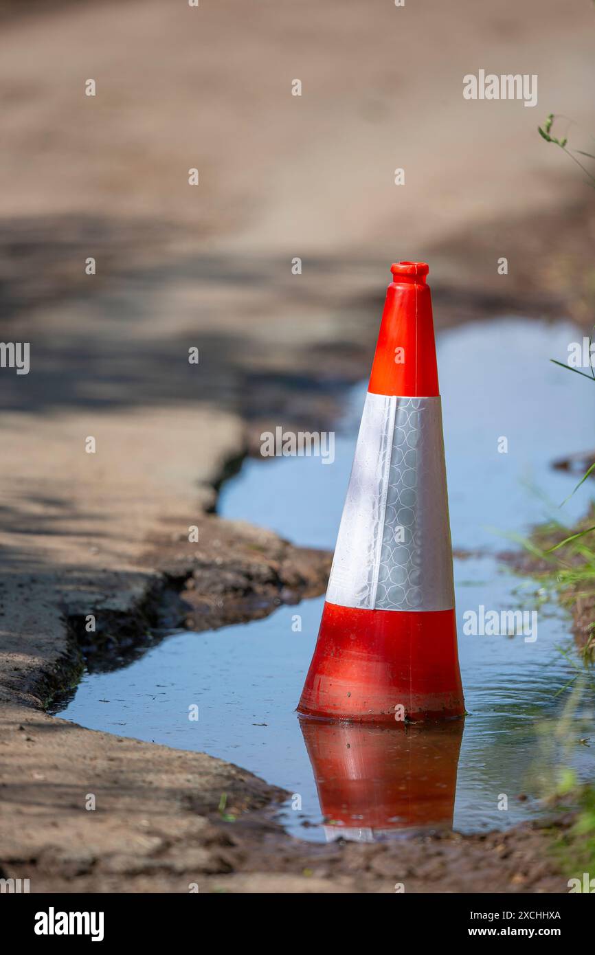 Vertical close up of deep pot hole in UK country lane filled with ...