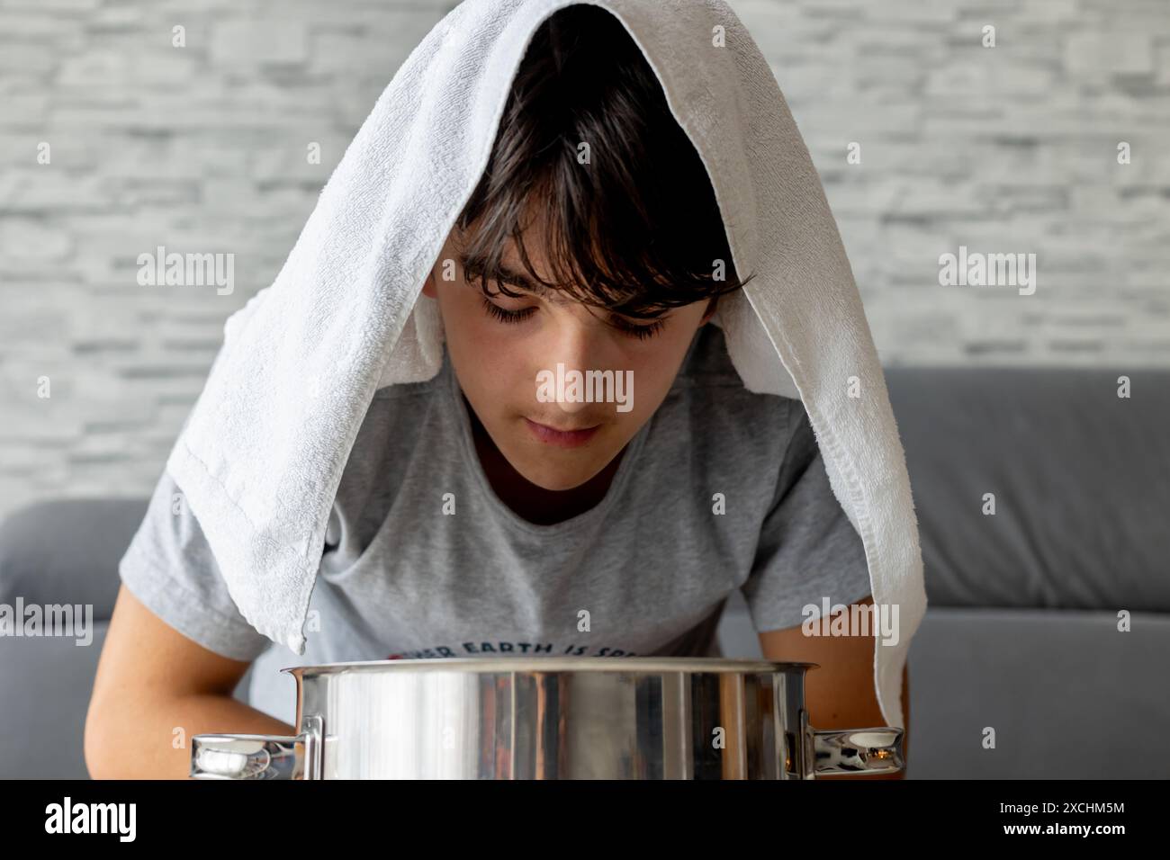 Teenage boy, child, doing steam inhalation at home to soothe and open ...