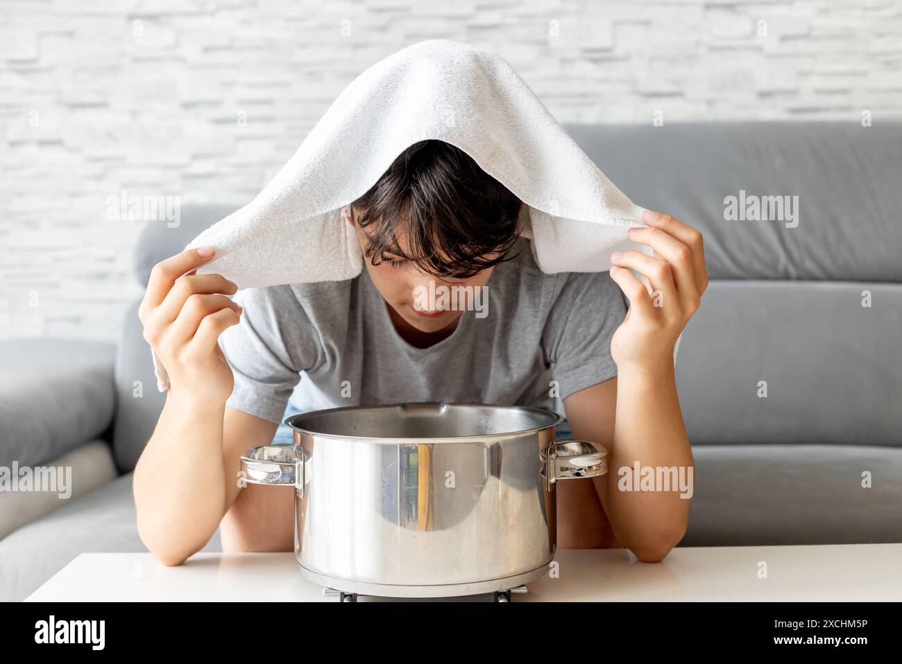 Teenage boy, child, doing steam inhalation at home to soothe and open ...