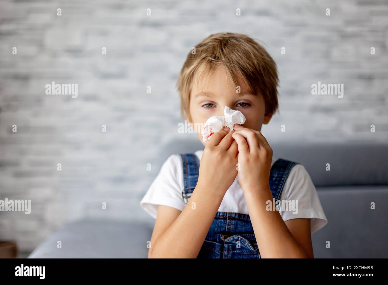 Child, holding pater tissue with blood, bleeding from the nose ...